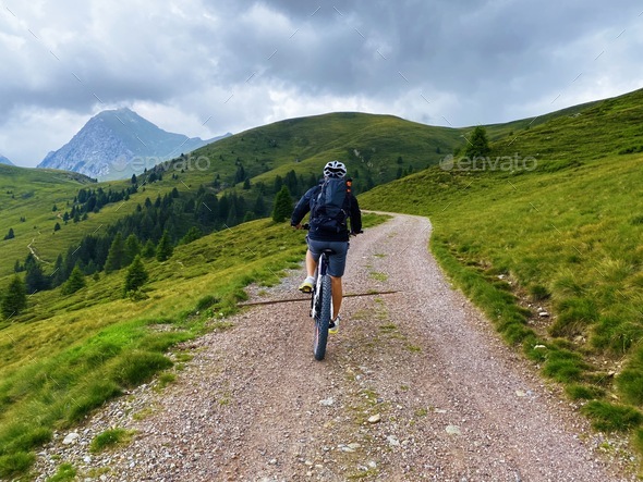 Rear view of single mountain bike rider on electric bike Stock Photo by ...