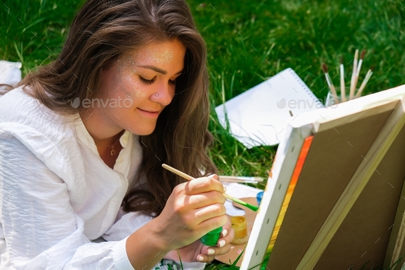 Artist painting on the easel outdoors in the garden. Open air outdoor ...