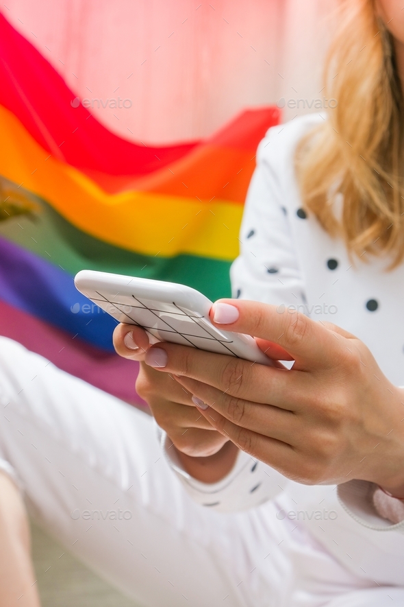 Young millennial hippie woman sitting on balcony using mobile phone ...