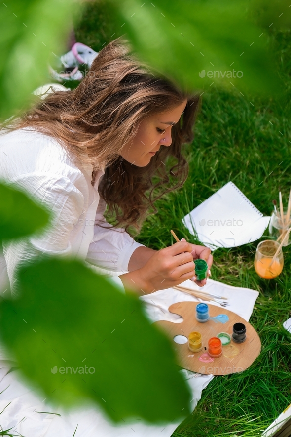 Artist painting on the easel outdoors in the garden. Open air outdoor ...