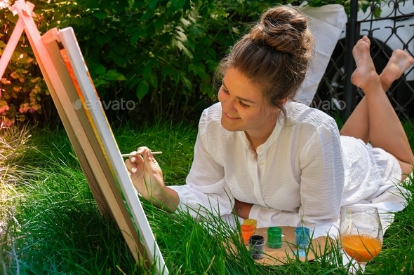 Artist painting on the easel outdoors in the garden. Open air outdoor ...