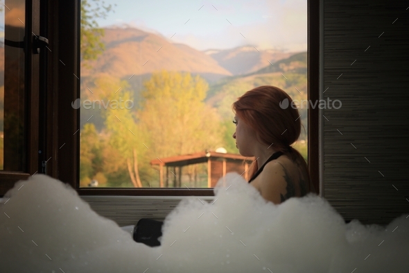 Girl in a fancy guest house looking trough the window form the jacuzzi ...