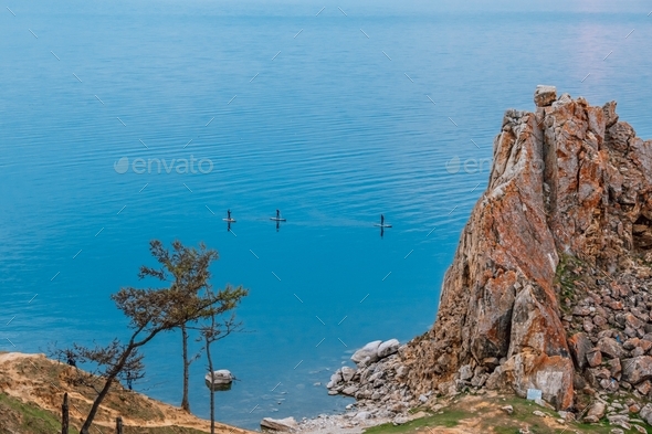 three people are swimming in the waters of Lake Baikal on sup surfboards. outdoor activities ...