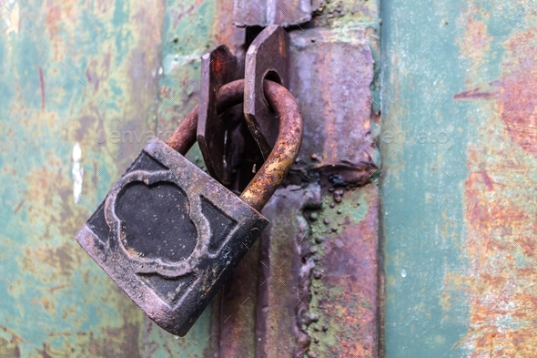 old and rusty padlock with scratches locks the steel doors of an ...