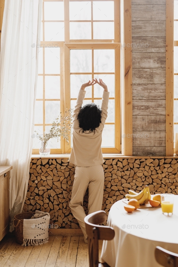 Back view of woman stretching in the morning in front of the window ...