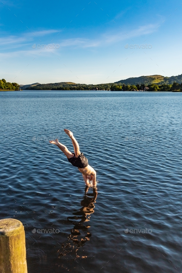 Teenage boy diving into a lake in England on a Summer evening. Making a ...