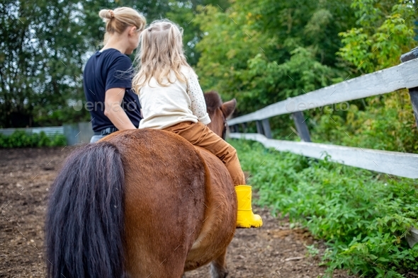 Happy girl riding a horse bareback for the first time. Rear view ...
