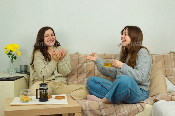 Playful young smiling women have fun drinking tea and talking telling ...