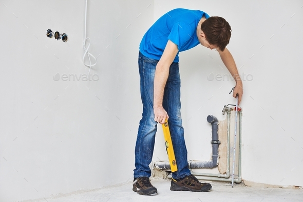 Plumber checks pipe vertical level after installation Man with level ...