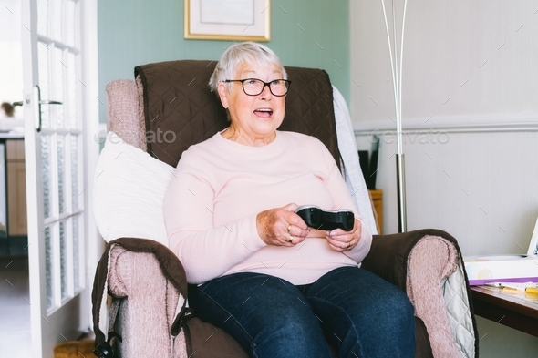 Emotional senior, mature woman looking at tv screen and using wireless ...