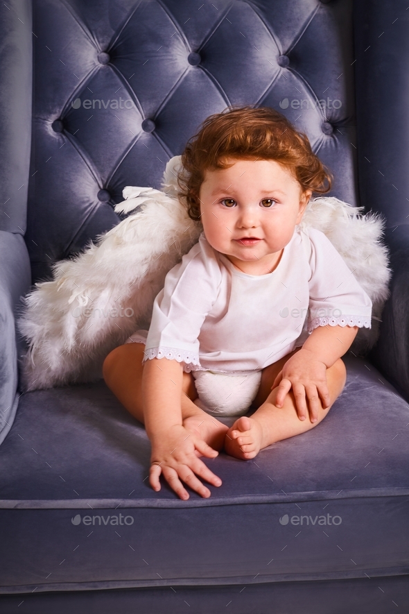 Little boy angel play at home. Little boy like angel smile and sit on ...