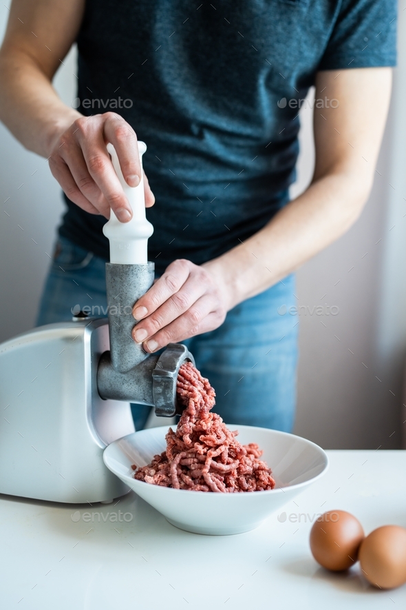 Man cooking minced meat using meat grinder. Fresh meat, eggs. Stock ...