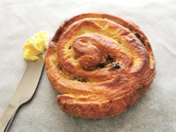 Raisin danish pastry swirl on parchment paper. Stock Photo by Maliflower73