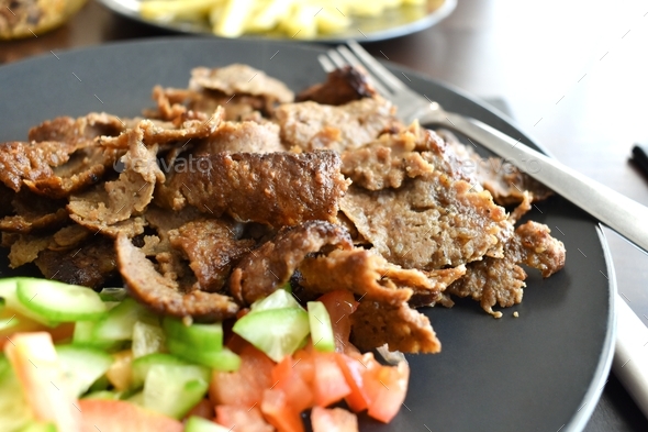 Meat Doner Kebab with vegetable salad on a black plate. Traditional ...