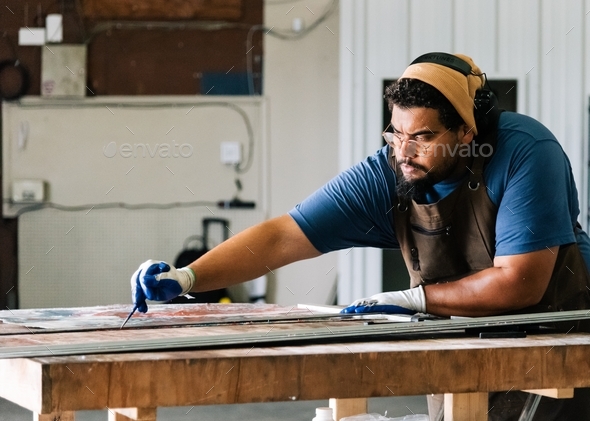 An artist / maker works on a sheet of melted recycled plastics he ...