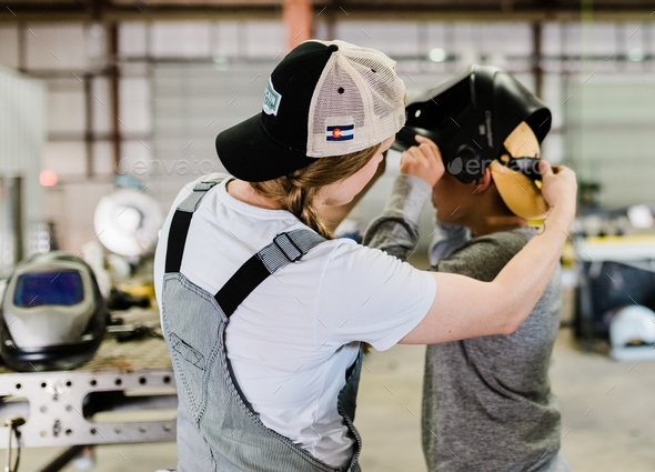 A female welder teaches a child how to weld - the first step is putting ...
