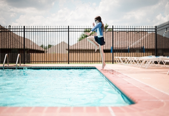 Girl jumps into the deep end of the pool on a cloudy summer day Stock ...