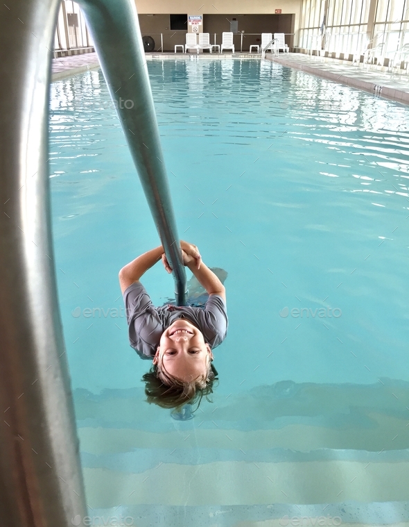 Hotel pool swimming - child hangs from hand rail Stock Photo by kytawillets