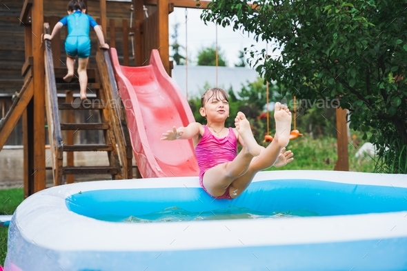 Staycation.Little girl in swimsuit swim,rolls down slide Inflatable ...