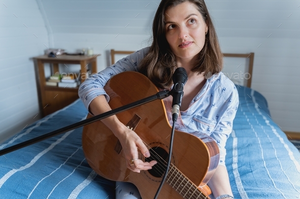 Young beautiful woman,musician,singer studying,practicing to play home ...
