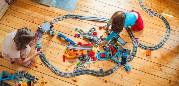 Girls, sisters play kids constructor, build toy railway, railroad by ...