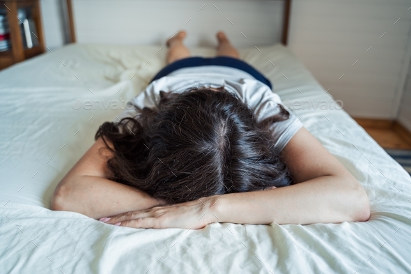Sad, unhappy woman lying on bed in depression. Headache,stress,anxiety ...