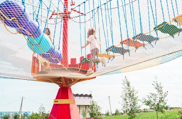 Small children have fun in rope amusement park. Suspended rides on top ...