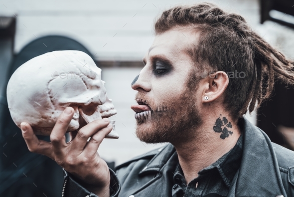 Scary man looks at skull,shows tongue.Celebrating halloween.Terrifying ...