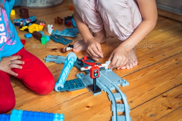 Girls, sisters play kids constructor, build toy railway, railroad by ...