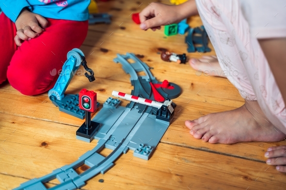 Girls, sisters play kids constructor, build toy railway, railroad by ...