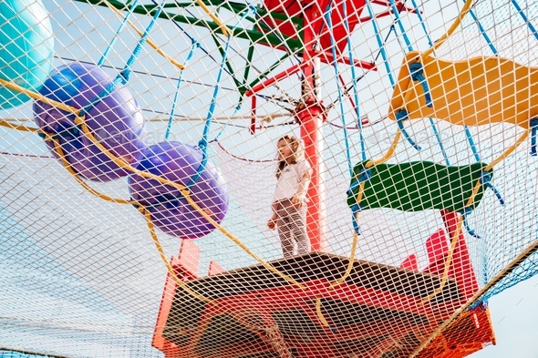 Small children have fun in rope amusement park. Suspended rides on top ...