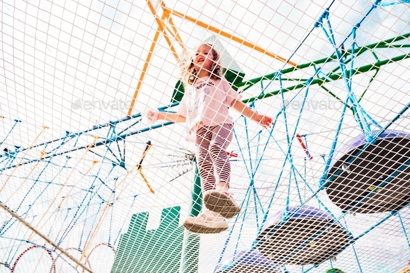 Small children have fun in rope amusement park. Suspended rides on top ...