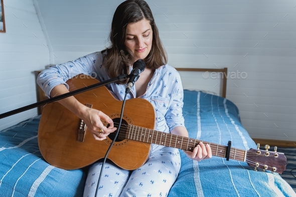 Young beautiful woman,musician,singer studying,practicing to play home ...