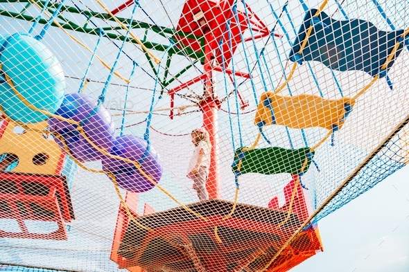 Small children have fun in rope amusement park. Suspended rides on top ...