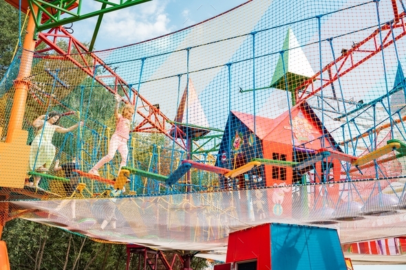 Small children have fun in rope amusement park. Suspended rides on top ...