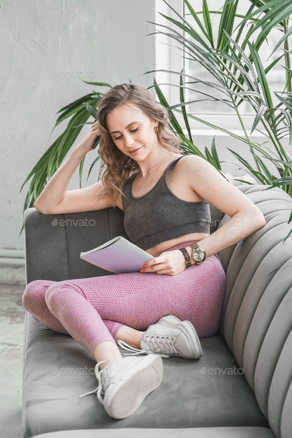 Young sporty slim woman yoga coach laying on sofa couch in sportswear ...