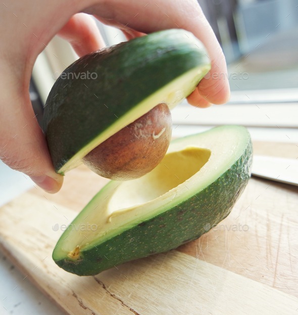 Avocado halved on the cutting board. Stock Photo by SmitBruins | PhotoDune