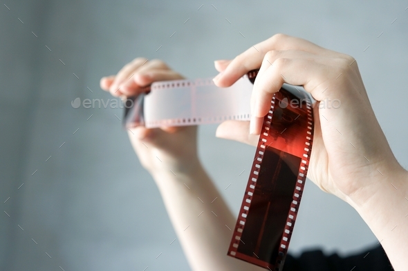 Analog photography on filmstrip . Hands holding photo negatives against ...