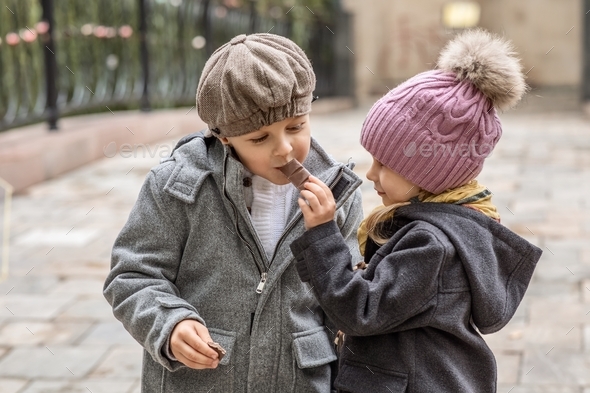 Two children on a walk in the park, after the rain, have fun eating a ...