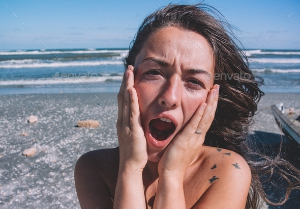 Woman on the beach having a surprised expression on her face. Stock ...