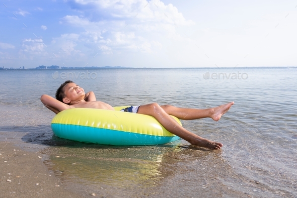 Boy sunbathing on tubing at the beach. Stock Photo by thanyapatm ...