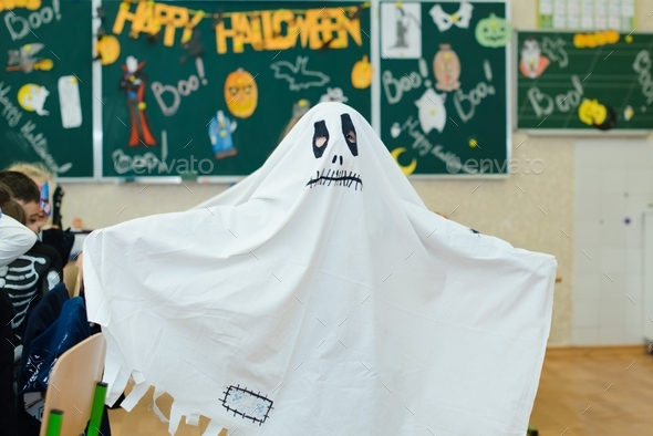 Kid in ghost costume in the school class during Halloween celebration ...