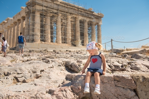Cute little girl sitting near the Parthenon of Athenian Acropolis ...