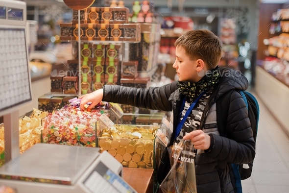Preteen boy choosing sweets in the confectionery. Boy buying candies in ...