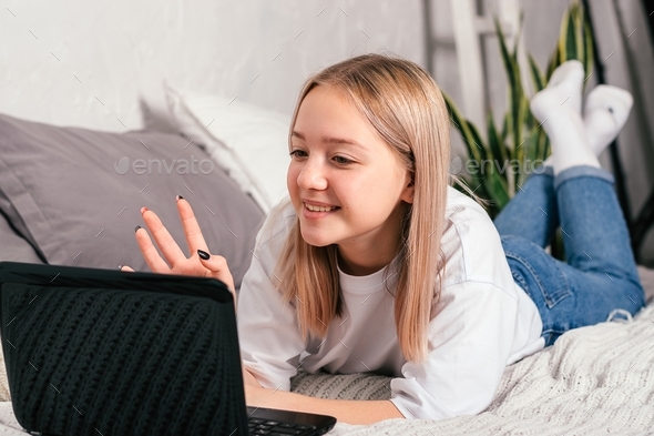 Video communication.Teenage girl lying on the bed and communicating via ...