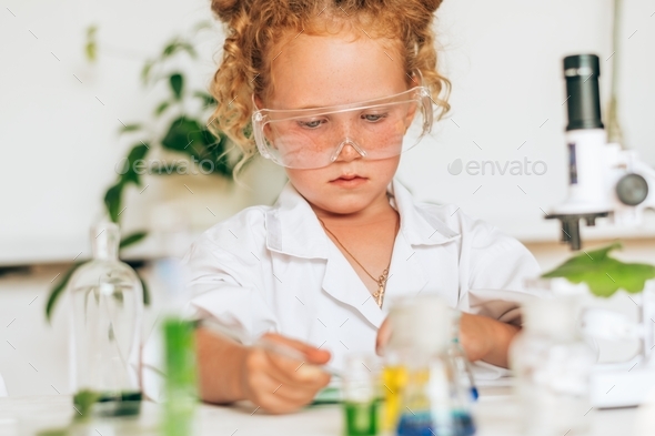Seven-year-old girl in a white uniform doing chemical experiments in ...