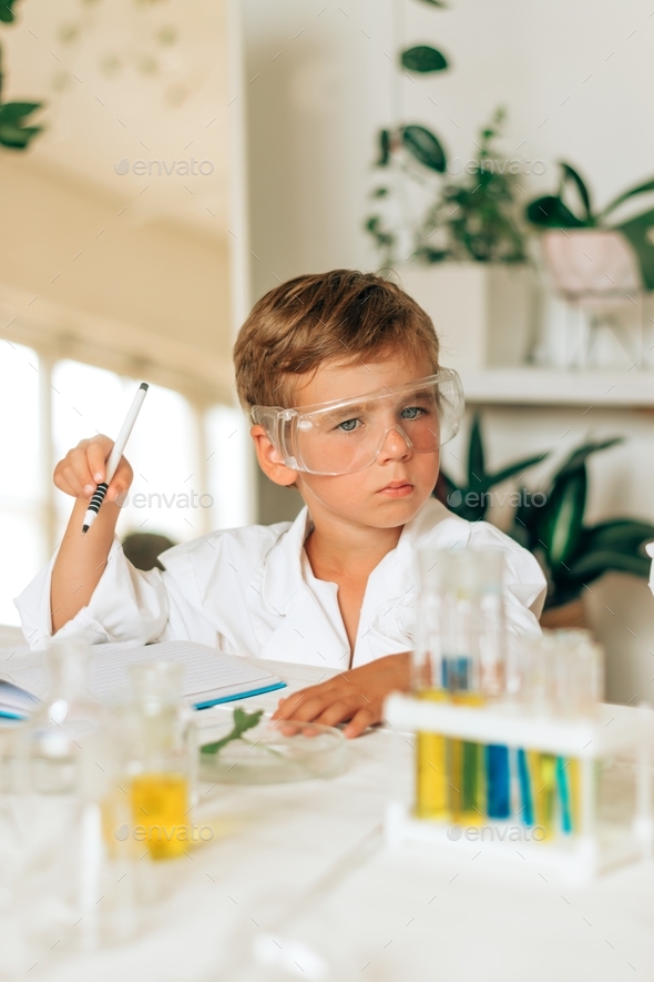 A five-year-old boy in a white uniform is doing chemical experiments in ...