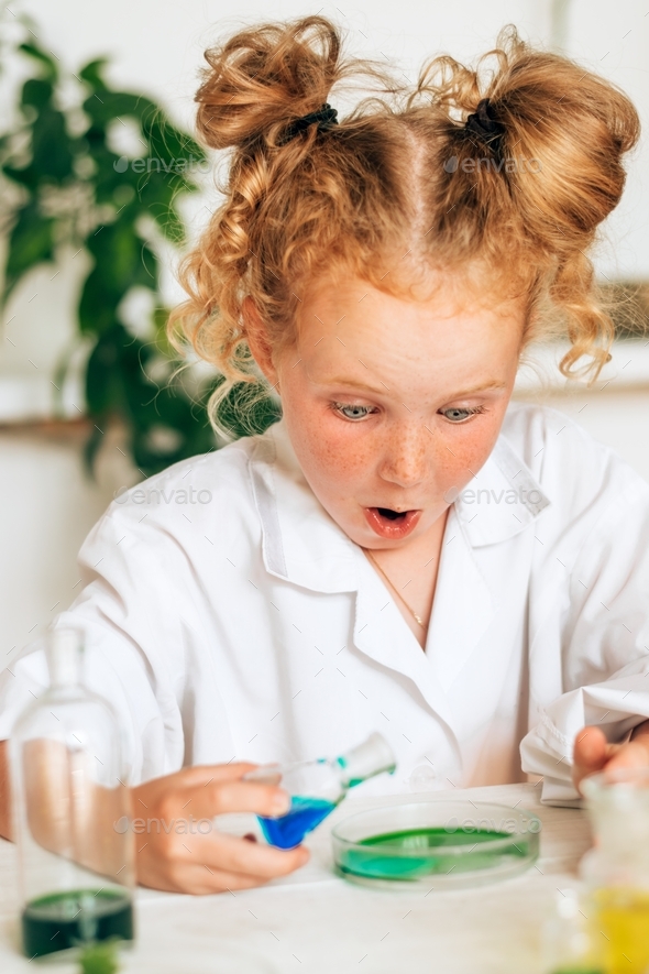 Seven-year-old girl in a white uniform doing chemical experiments in ...