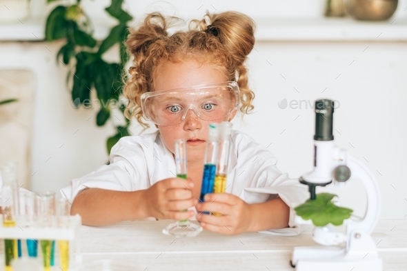Seven-year-old girl in a white uniform doing chemical experiments in ...