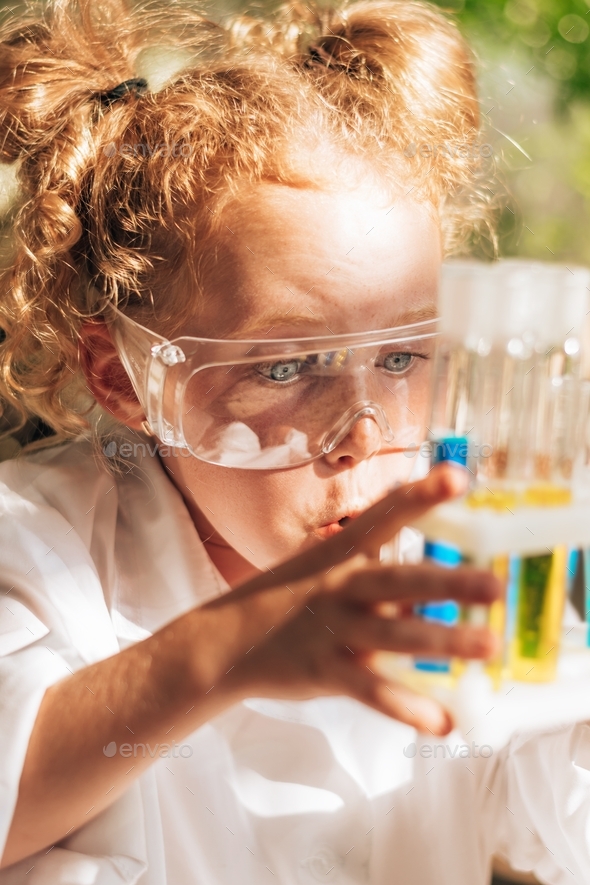 Seven-year-old girl in a white uniform doing chemical experiments in ...